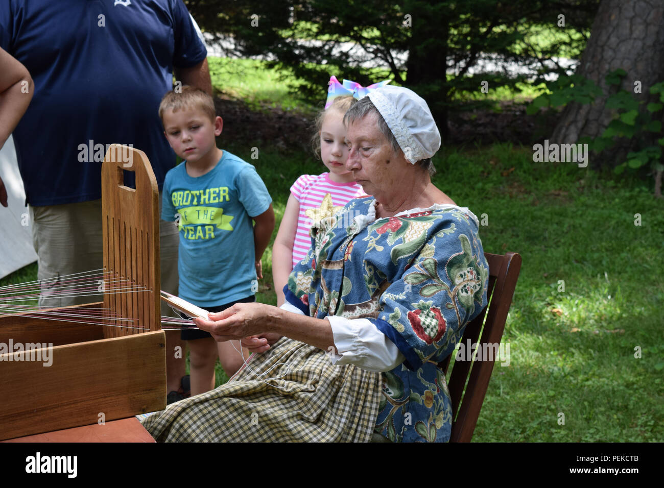 A woman giving a demonstration of using a Hand Loom from colonial times ...