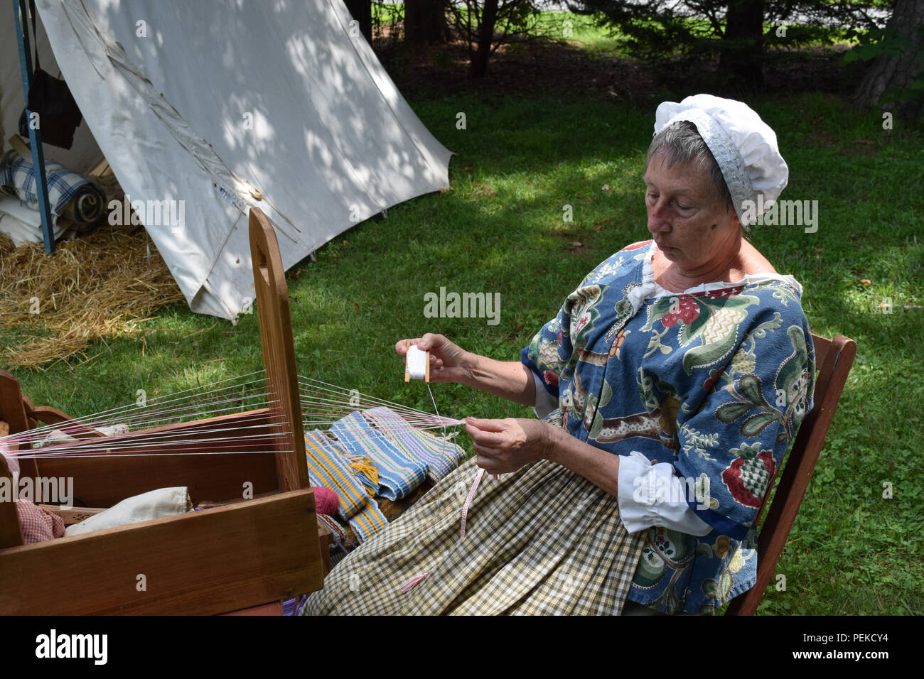 A woman giving a demonstration of using a Hand Loom from colonial times ...