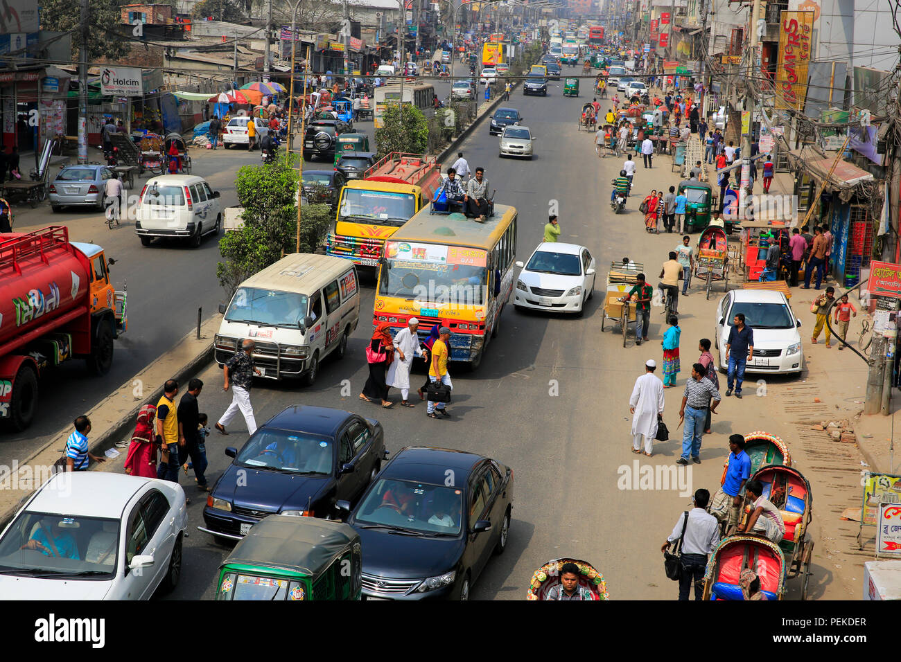 Pedestrians cross a busy road putting their lives at risk. Dhaka ...