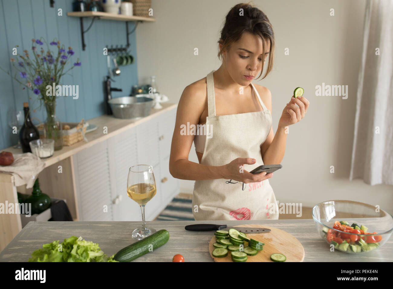 A woman in an apron prepares and uses a smartphone Stock Photo - Alamy