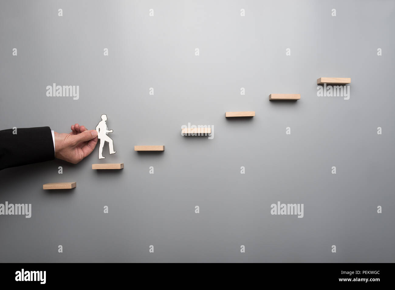 Businessman in white shirt building a graph or ladder of success on ...