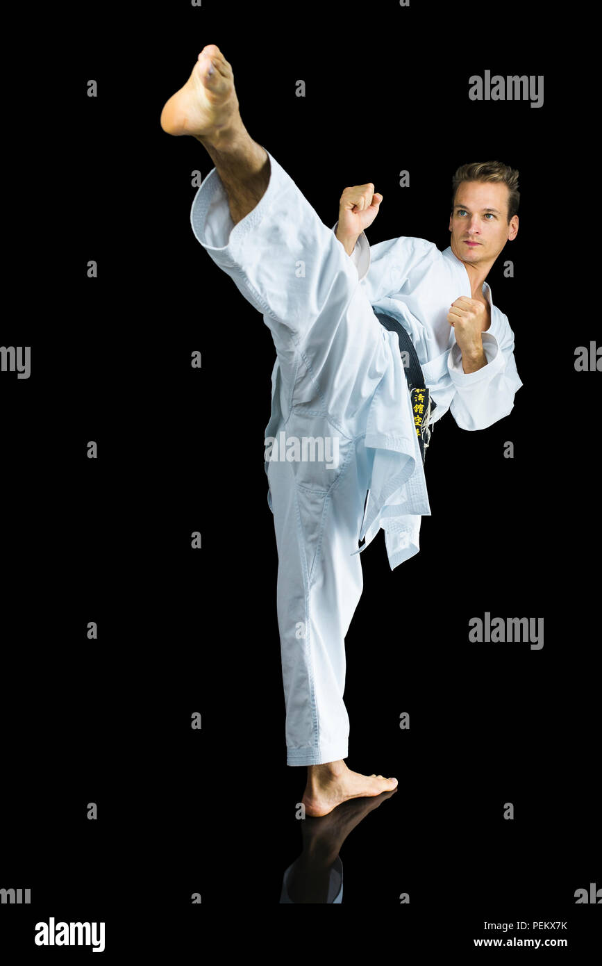 Young man in white kimono training karate kicking his leg at you ...