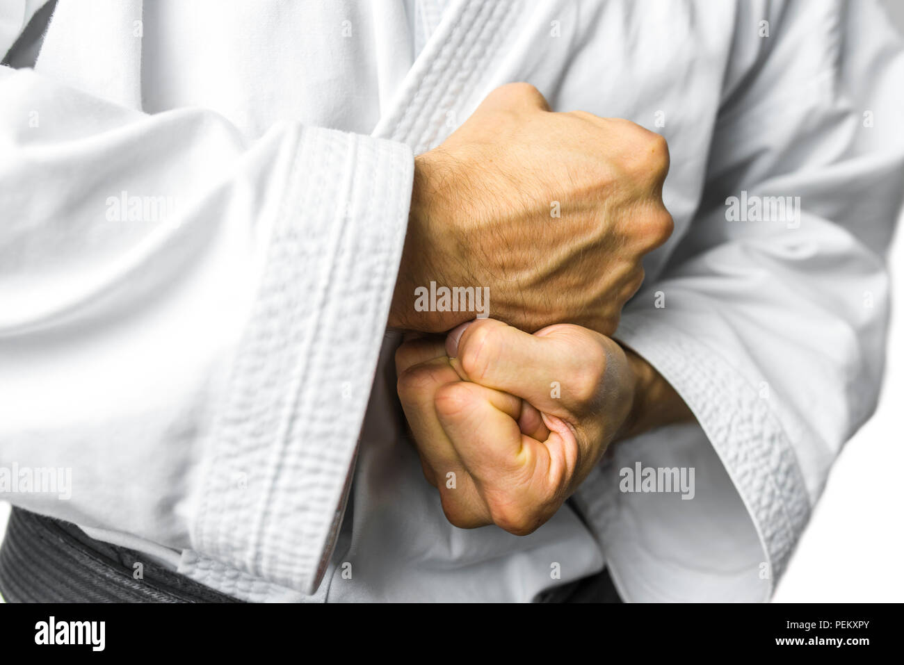 Closeup of male karate fighter in white kimono making strong fists with ...