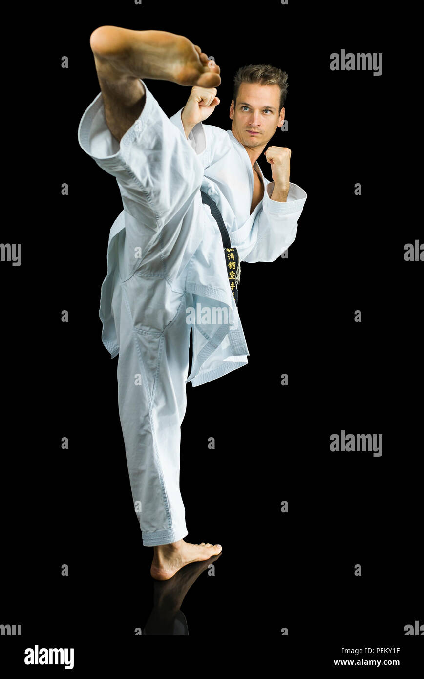 Professional karate fighter kicking. Isolated over black background ...