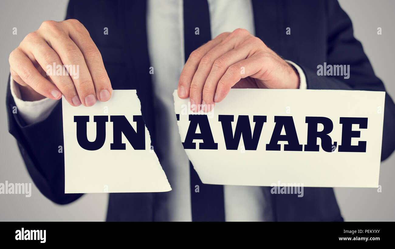 Businessman tearing up a sign saying - Unaware - conceptual of ...