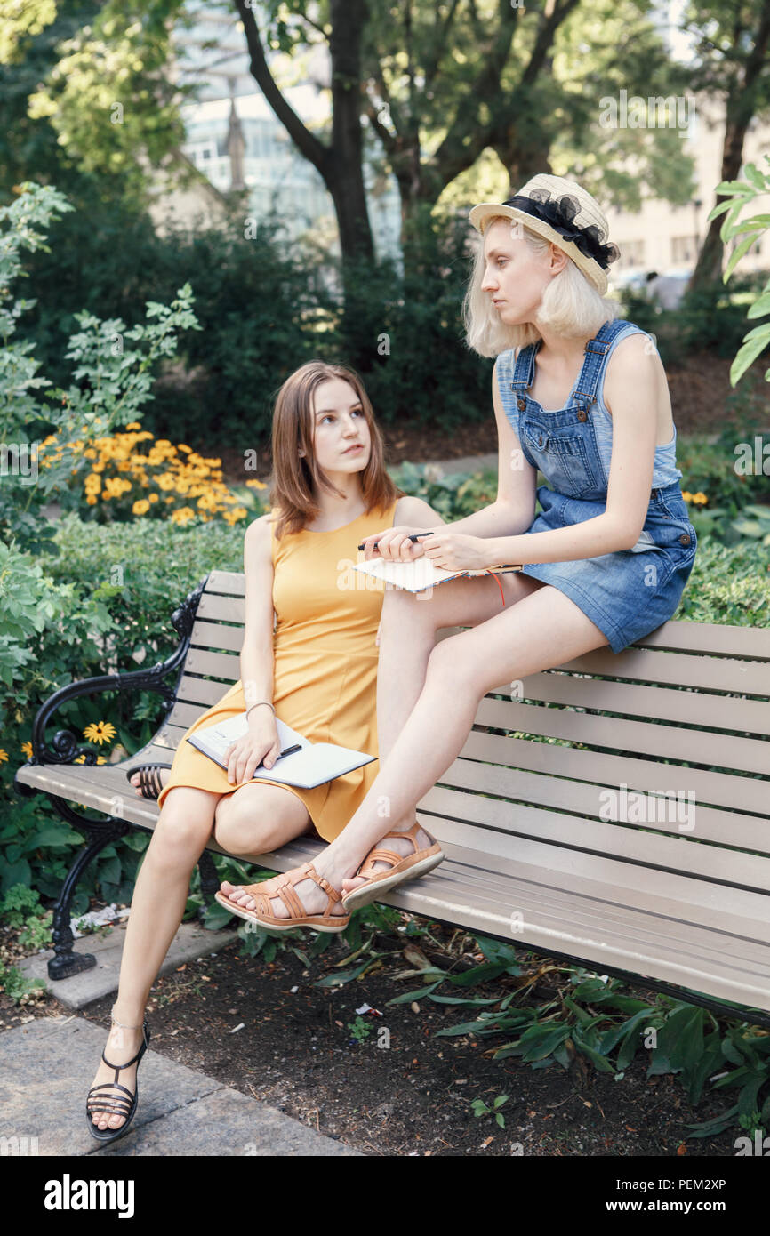 Two girls talking on bench hi-res stock photography and images - Alamy