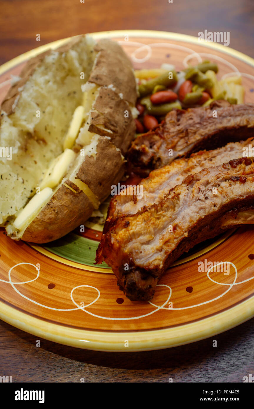 American BBQ bone-in ribs with buttered baked potato and green bean ...