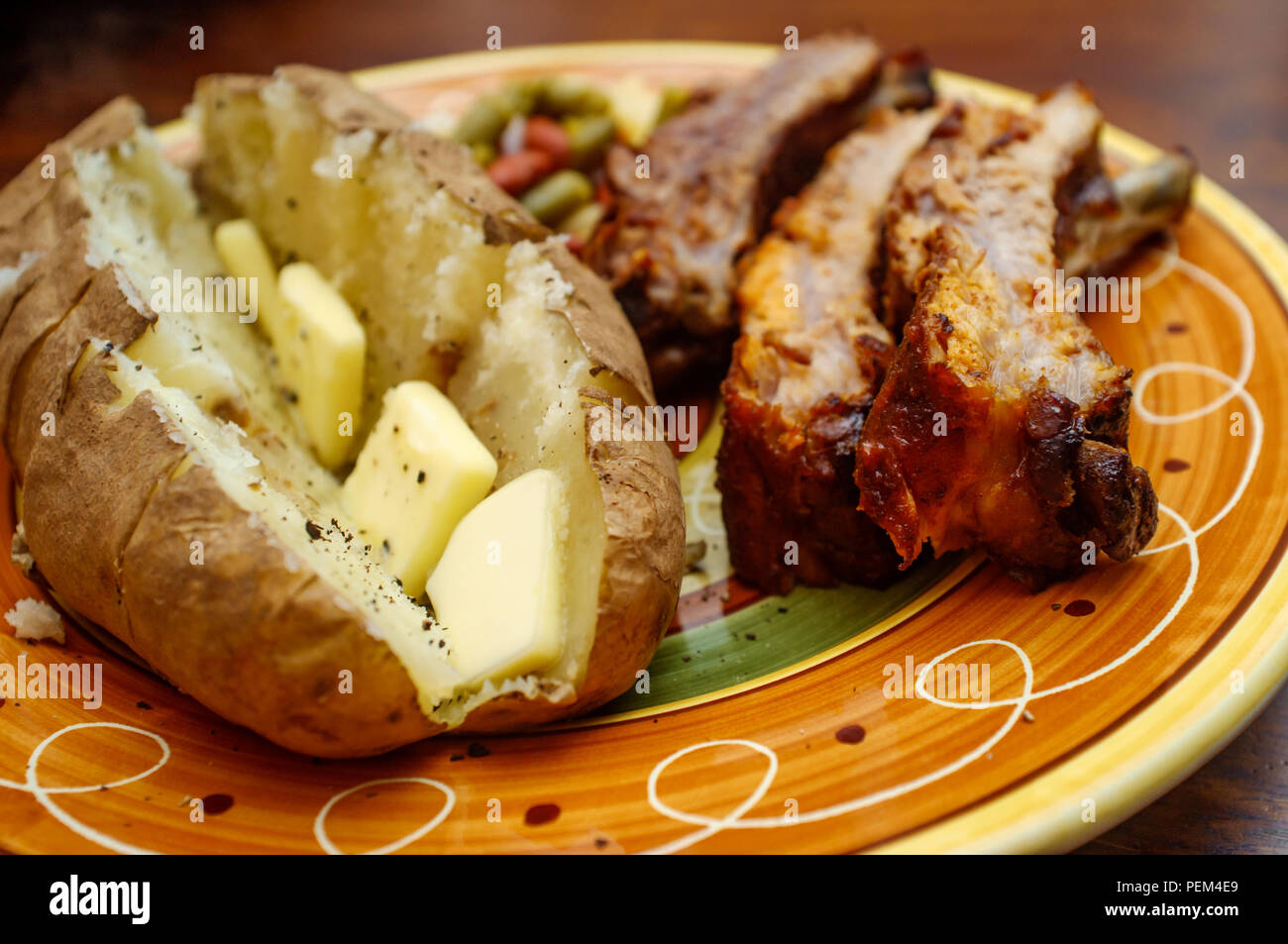 American BBQ bone-in ribs with buttered baked potato and green bean ...