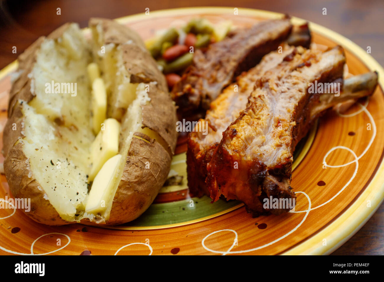 American BBQ bone-in ribs with buttered baked potato and green bean ...