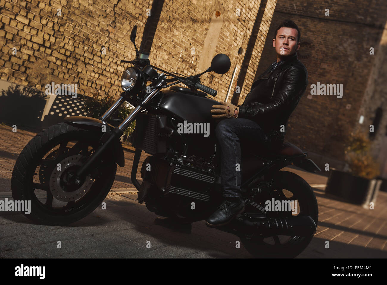 Man sitting on a cafe-racer motorcycle outdoors Stock Photo - Alamy