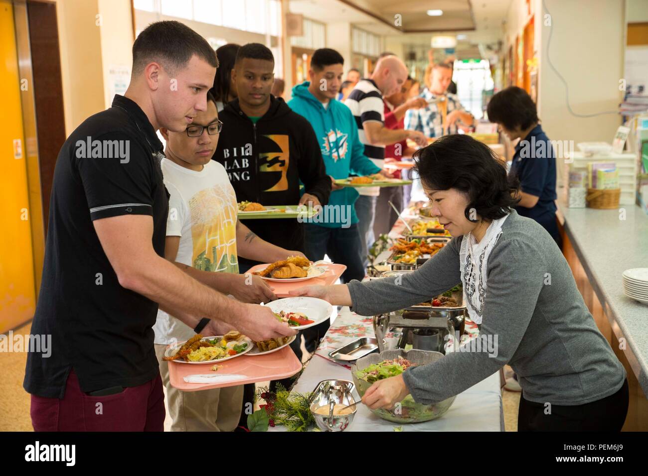 Junko Kurata, right, serves salad to Cpl. Jonathan Koren during a Christmas Party thrown by the ...