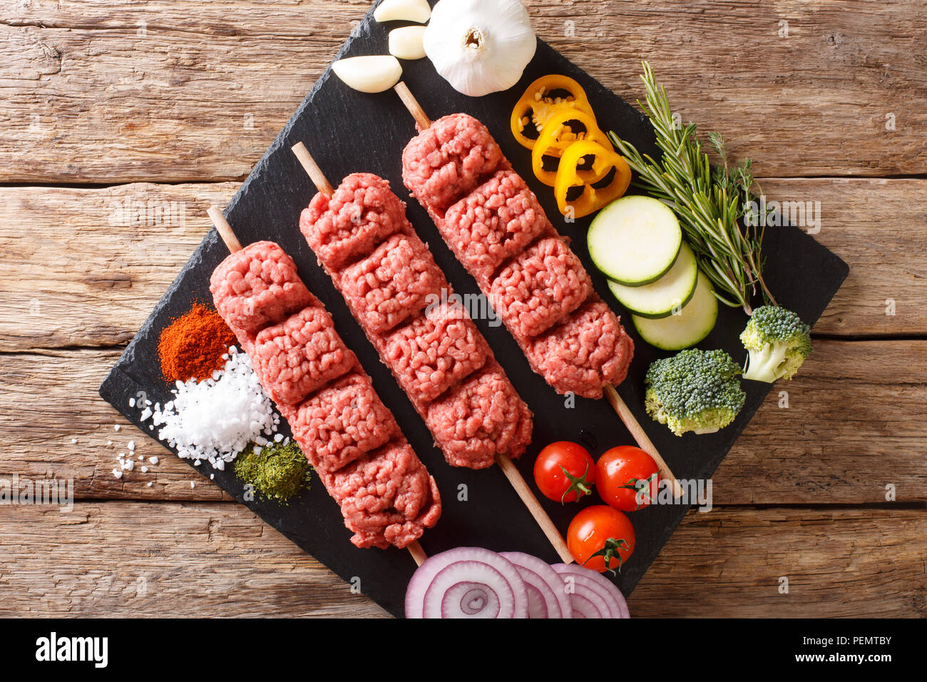 raw kebab of ground beef with ingredients and vegetables close-up on ...