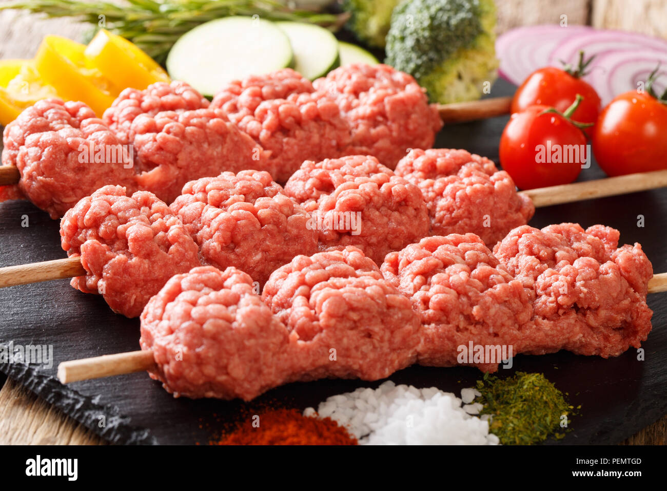 raw kebab of ground beef with ingredients and vegetables close-up on ...