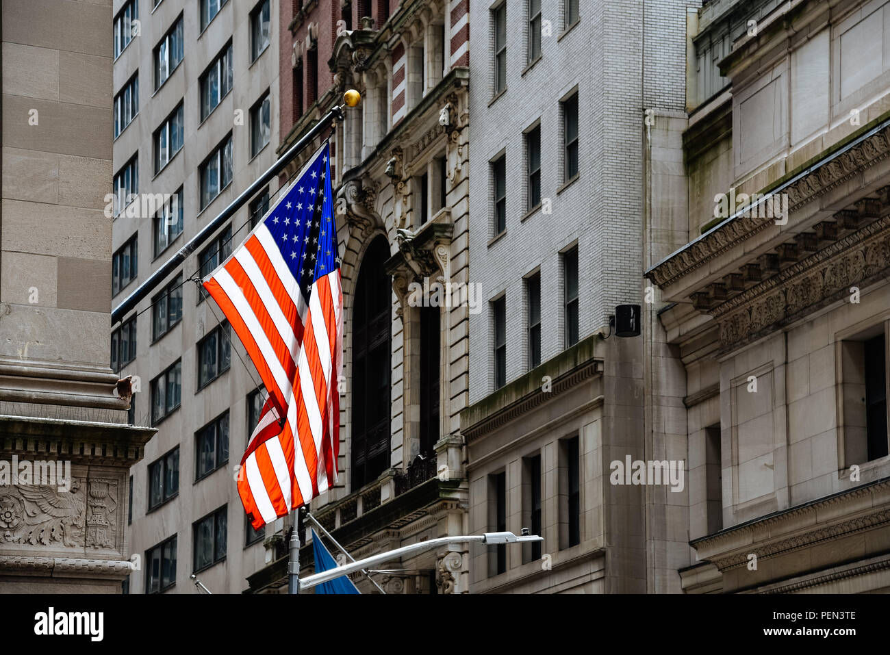 American flag waving against buildings in Wall Street in New York Stock ...