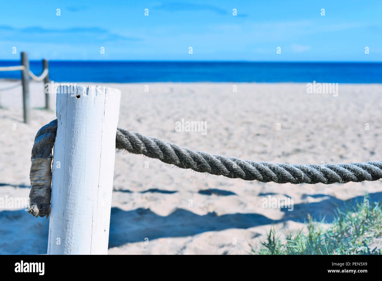 Beach holiday or relaxation scene with sea and sand. Weathered rope or ...