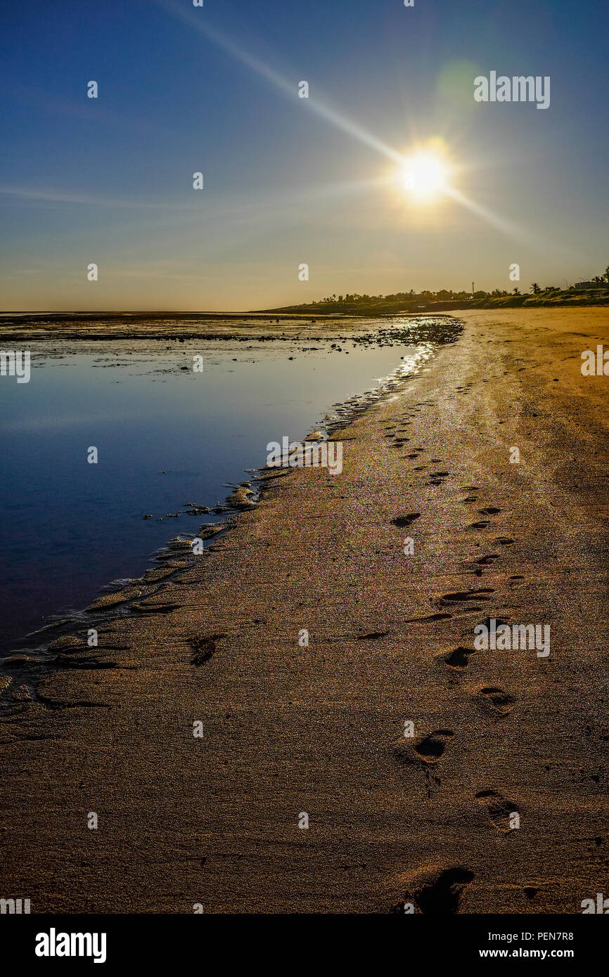 Sun rising over ocean and beach with footprints in sand Stock Photo - Alamy