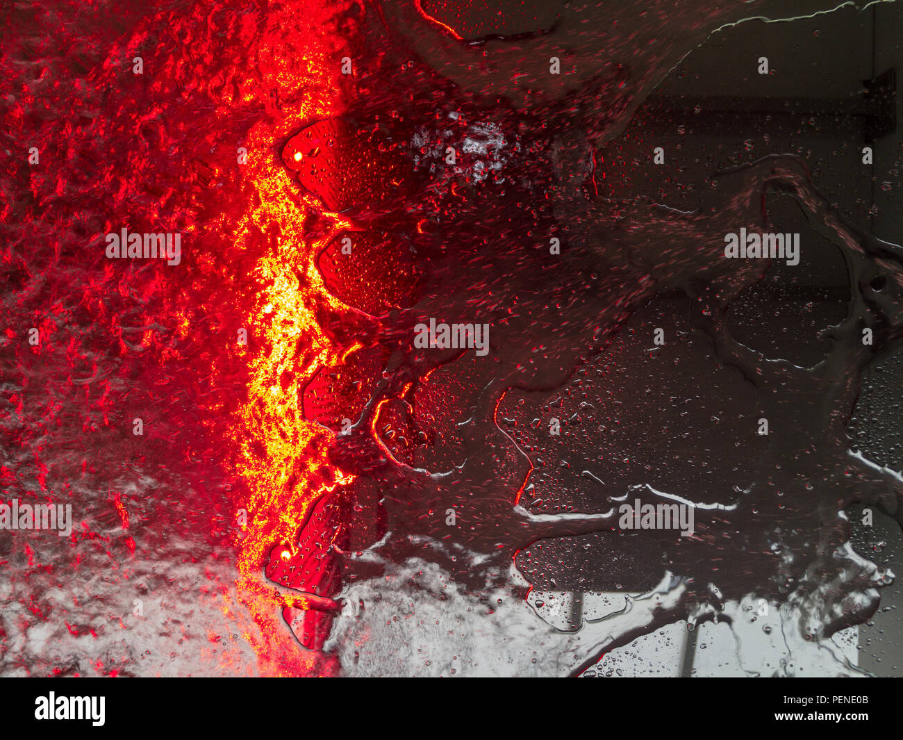 Running water on a windshield from inside a car with a red light stripe ...