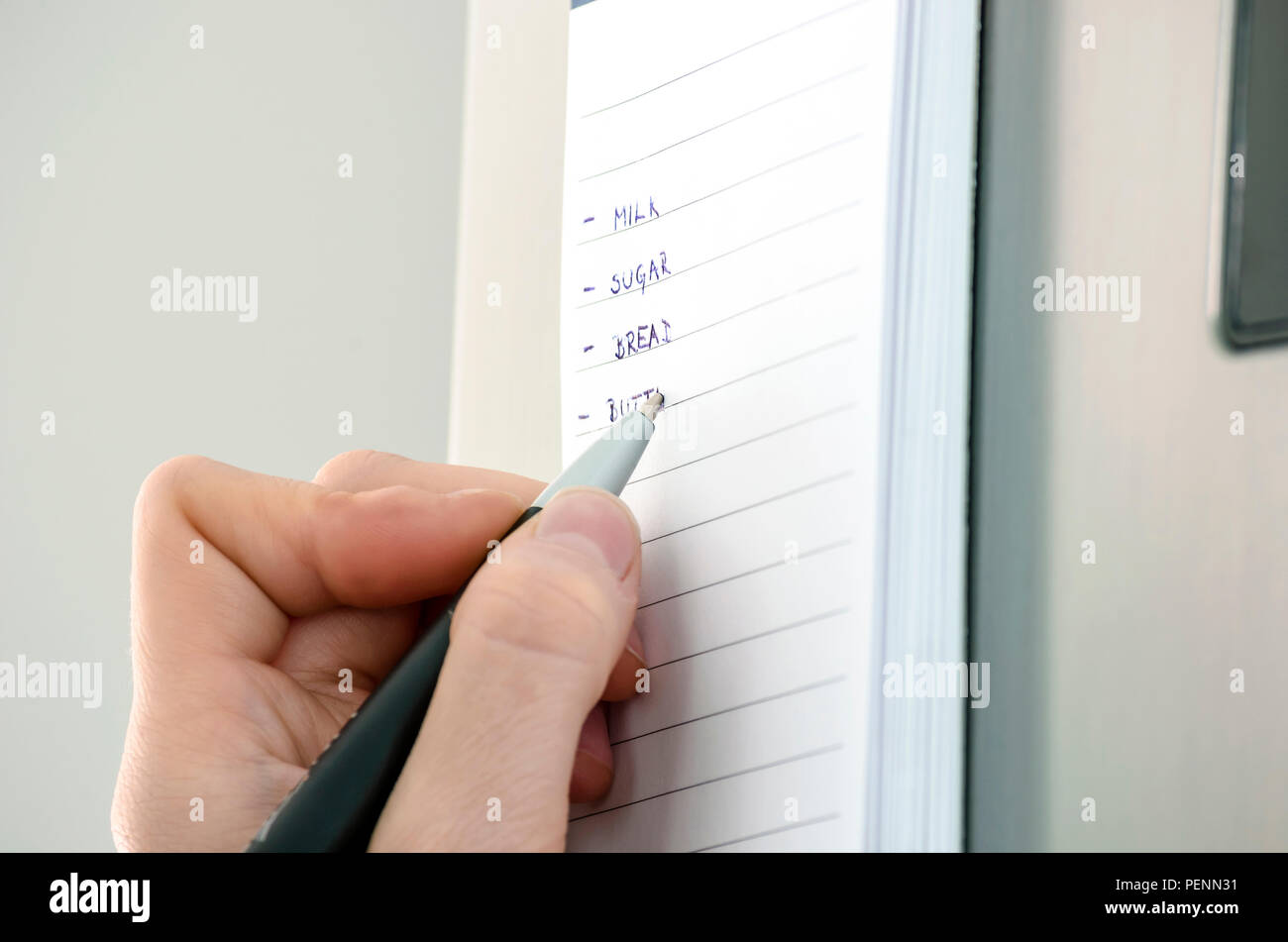 Female hand writing grocery list on a sticky reminder note on a ...