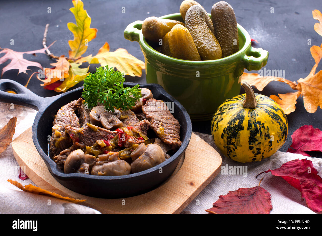 fried meat with mushrooms in a frying pan. on a black background. Lunch ...