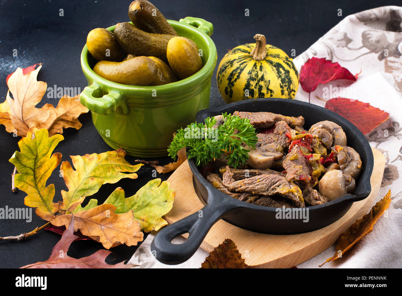 fried meat with mushrooms in a frying pan. on a black background. Lunch ...