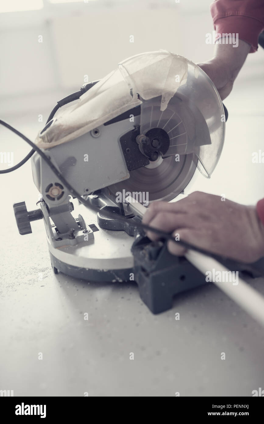 Retro effect faded and toned image of a workman using an electric ...