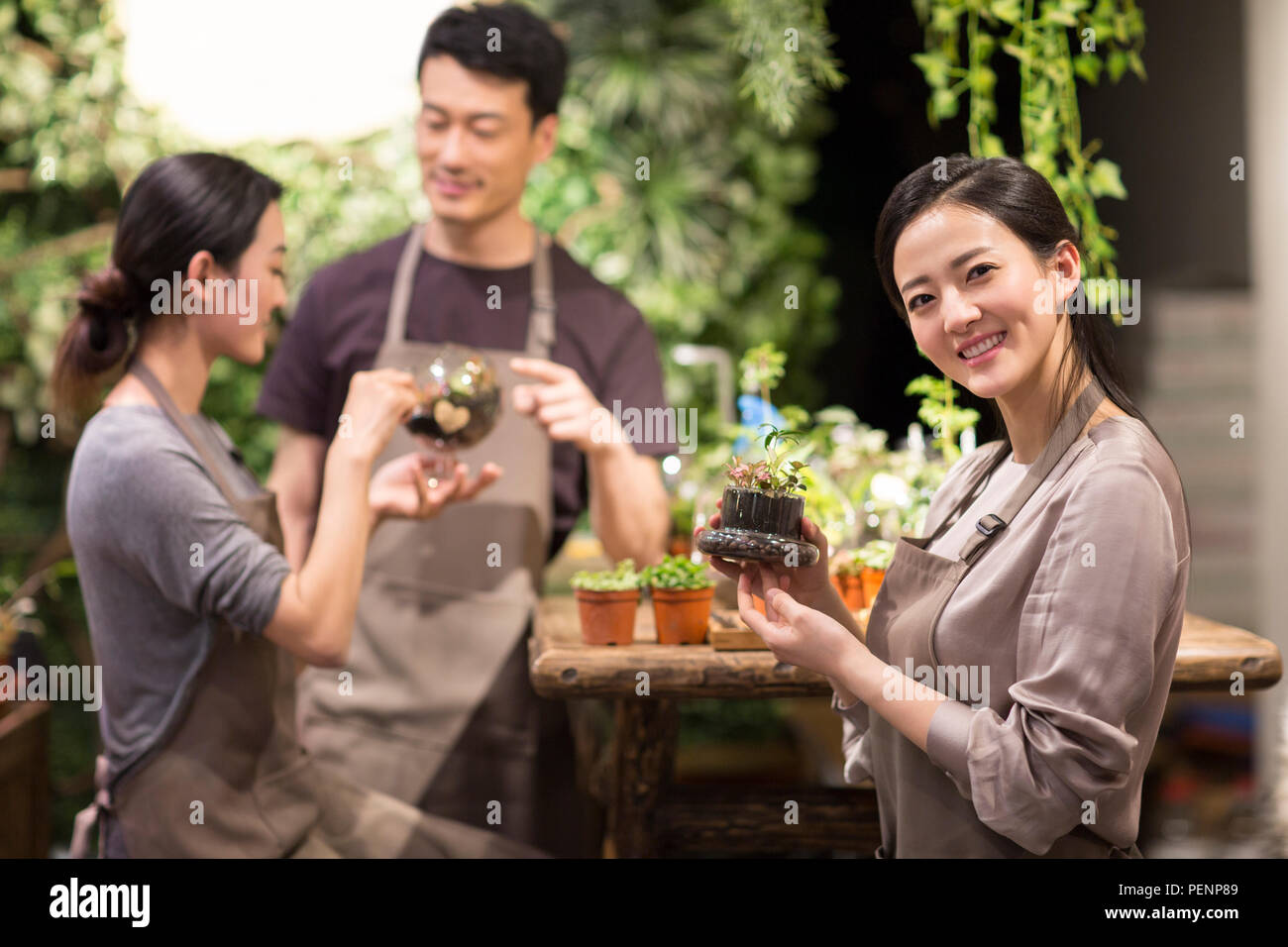 Happy young colleagues working in plant shop Stock Photo - Alamy