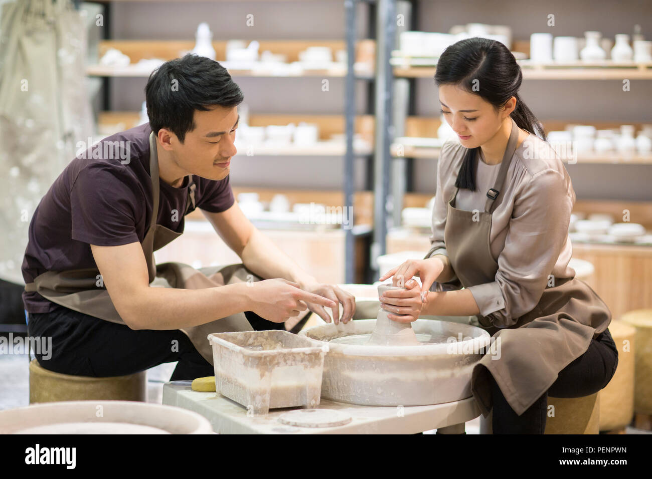 Potter teaching young woman making pottery Stock Photo - Alamy