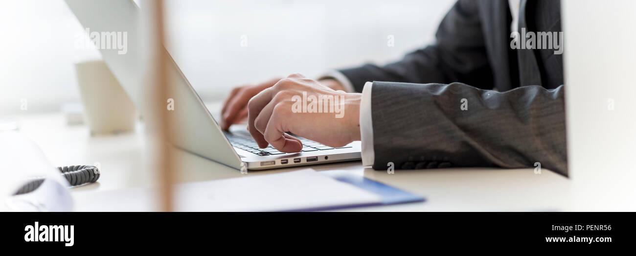 Wide cropped view of a businessman navigating the internet on his ...
