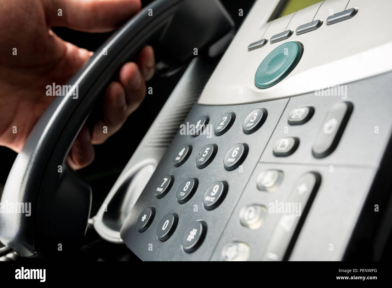 Closeup of landline office telephone with male hand holding its ...