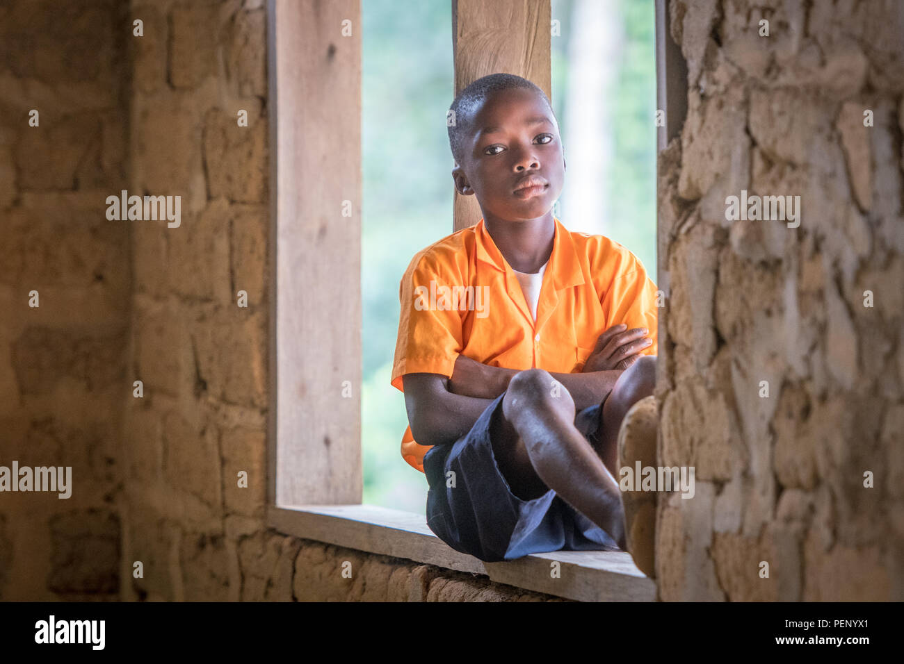 A young boy poses for the camera in a wooden window sill in Ganta ...