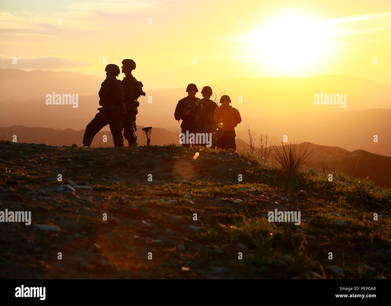 Marines look over the hill tops at their targets as the sun sets at ...