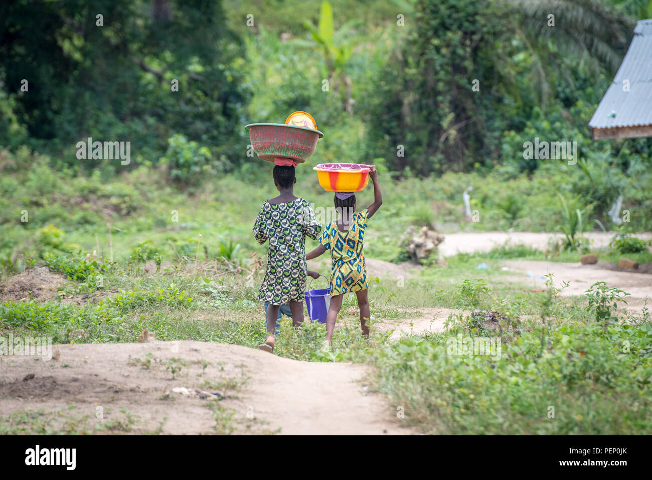 Two young girls carry colorful buckets on their heads in Ganta Liberia ...