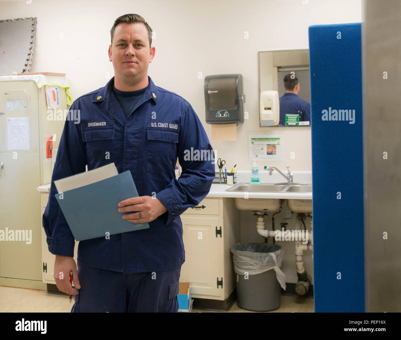 Coast Guard Petty Officer 2nd Class Ryan Shoemaker stands in a room of ...