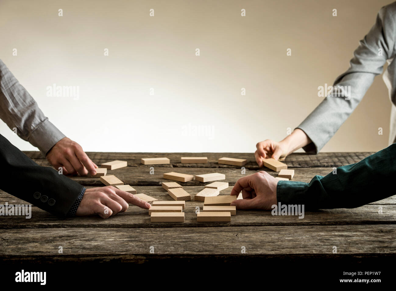 Business people arranging wooden blocks into the shape of a light bulb ...