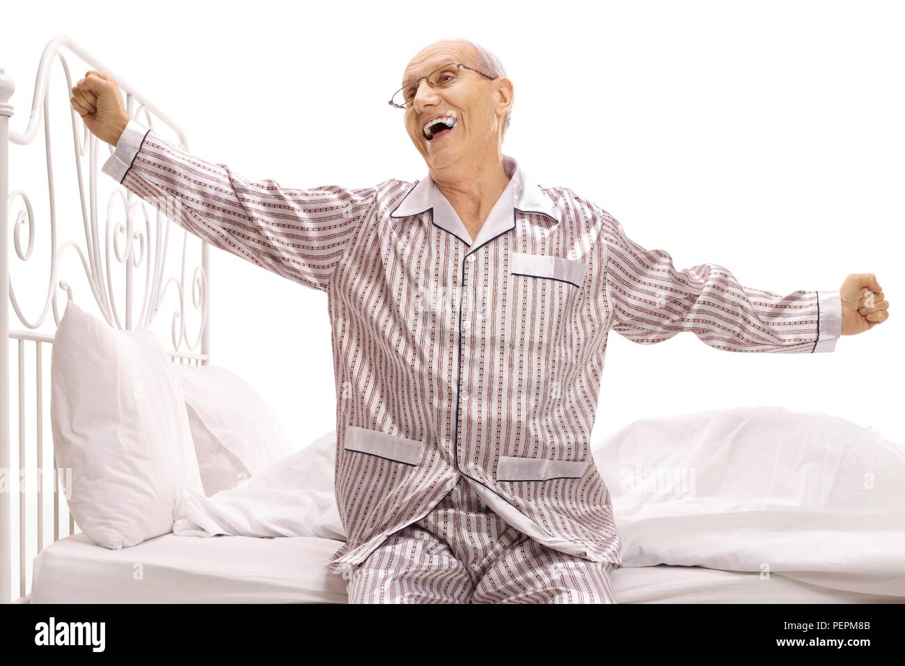 Elderly Man In Pajamas Sitting On A Bed Stretching Himself Isolated On