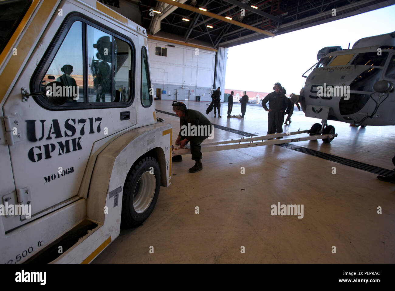 A Marine hooks a tow bar to an A/S32A-45, Aircraft Mid-Range Tow ...