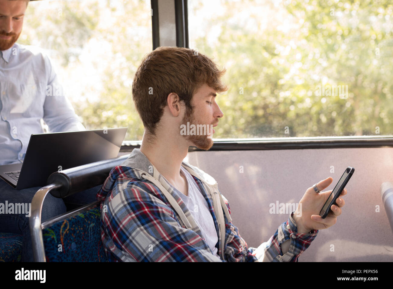 Male commuter using mobile phone while travelling in modern bus Stock ...