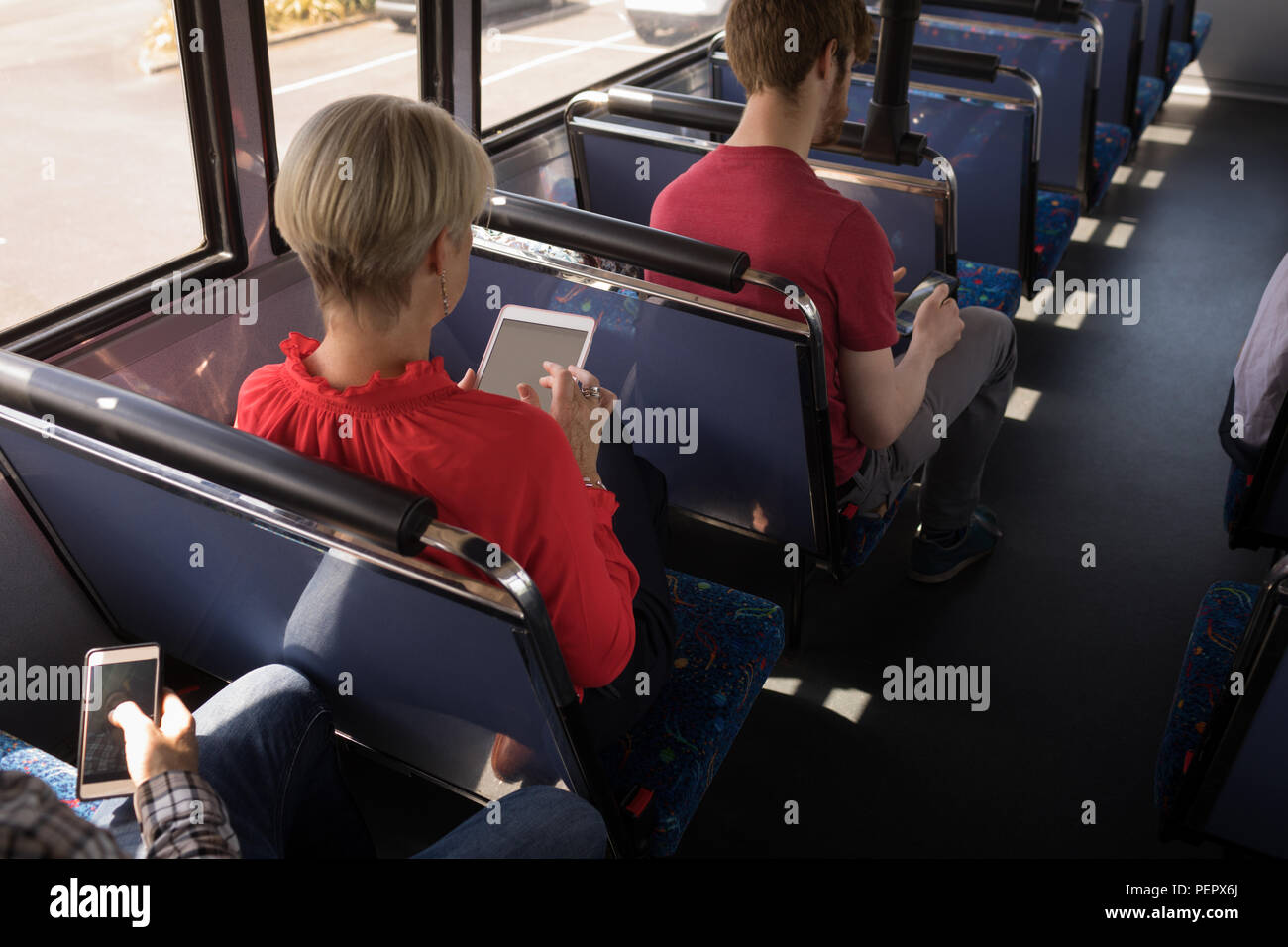 Female commuter using digital tablet while travelling in modern bus ...