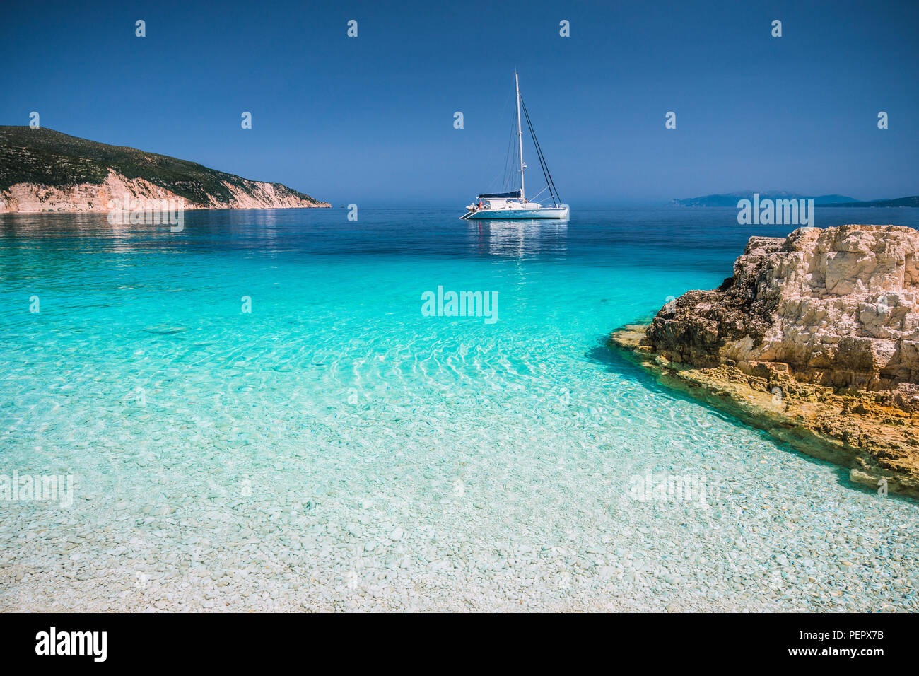 Beautiful azure blue lagoon with sailing catamaran yacht boat at anchor ...