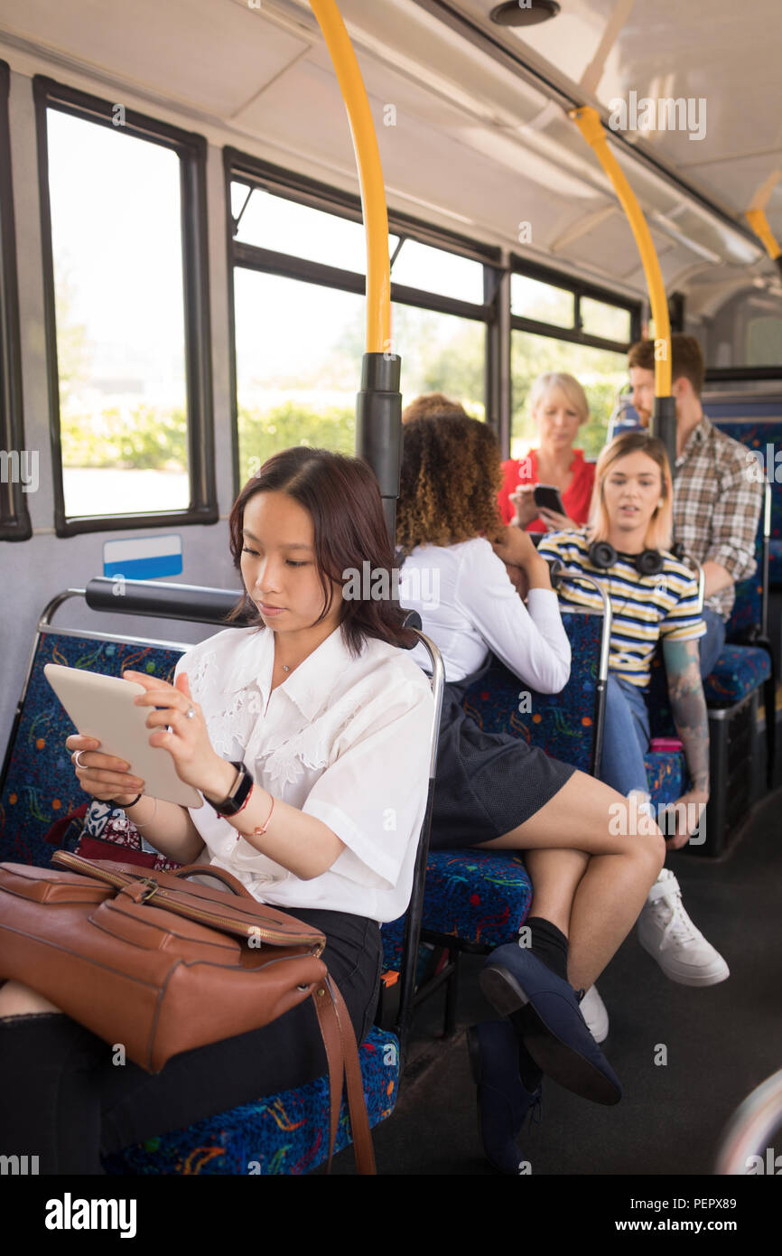 Female commuter using digital tablet while travelling in modern bus ...