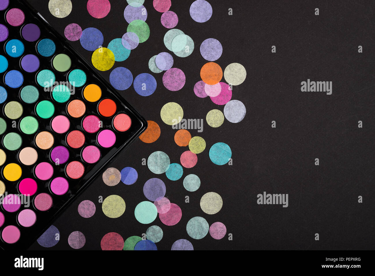 Makeup eyeshadow palette with colorful confetti scattered on black ...