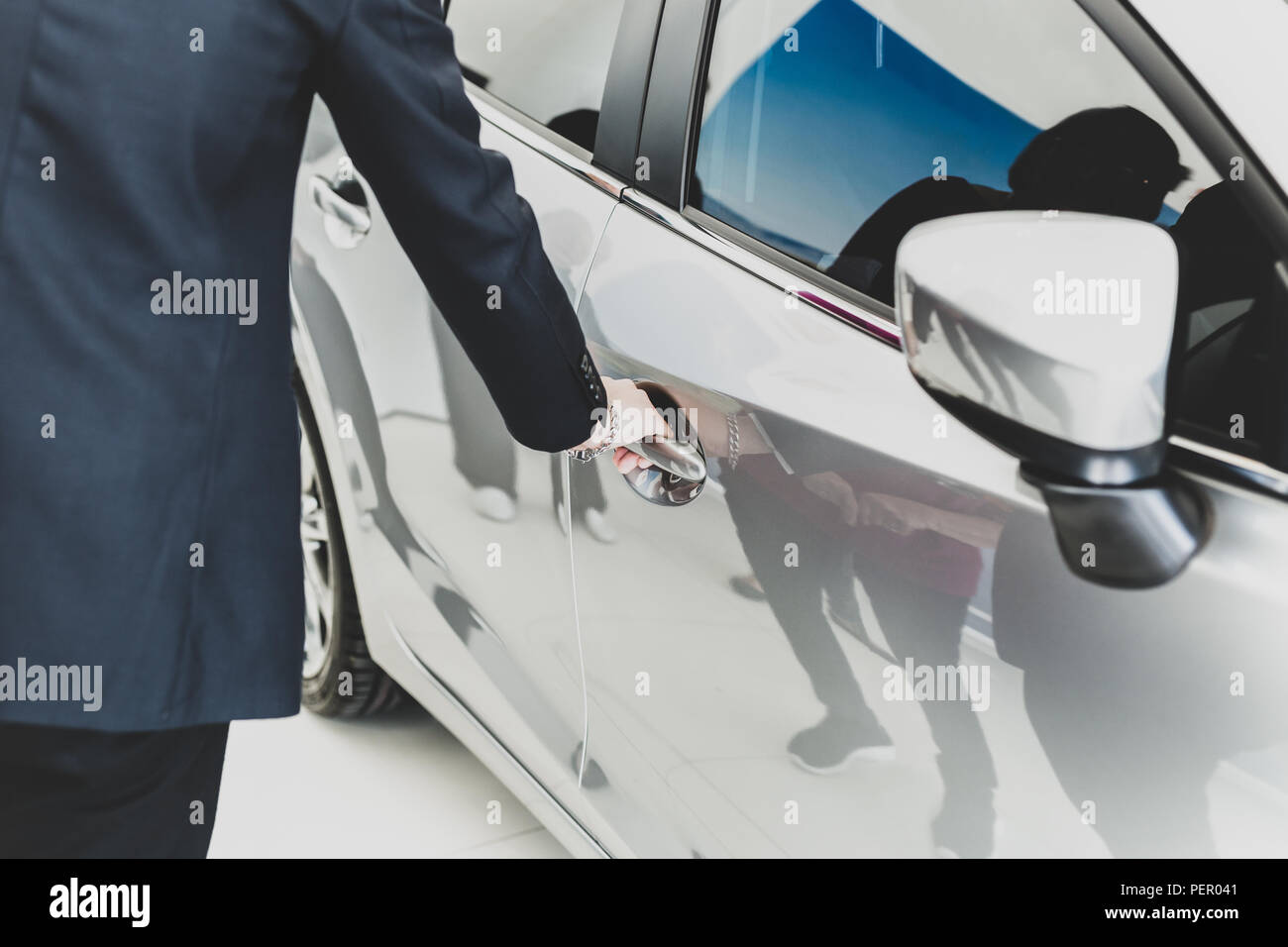 Family looking for new car with salemans hand on handle opening a car ...