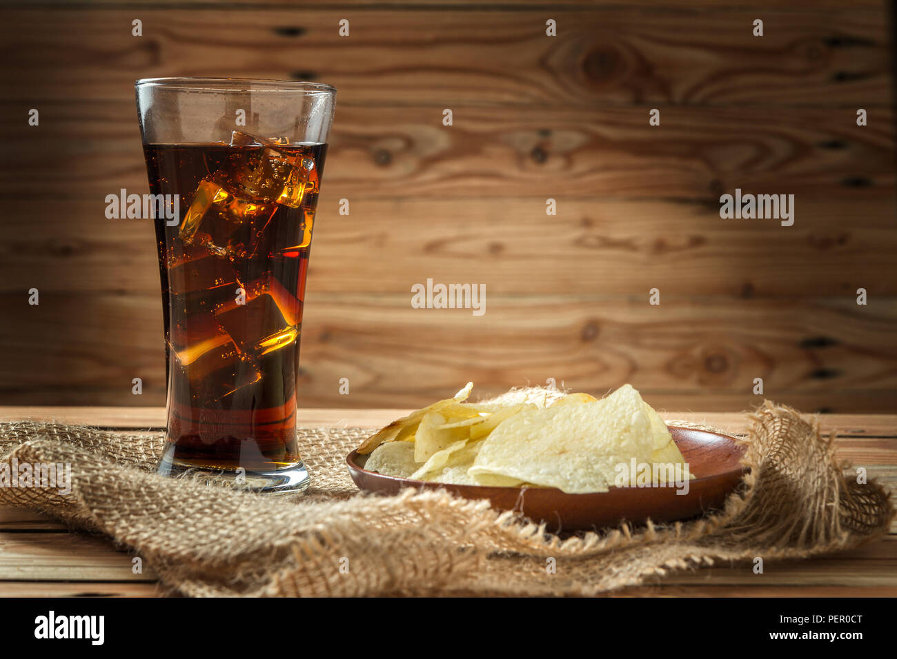 Potato chips with cola on a wooden background Stock Photo - Alamy