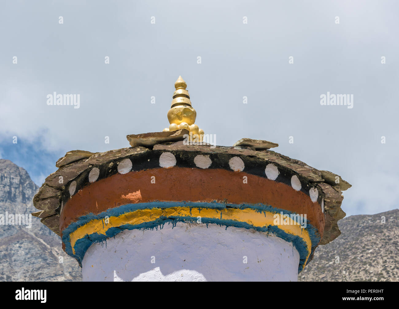 Multi-colored stone stupa with a bronze tip against the grey sky, Nepal ...