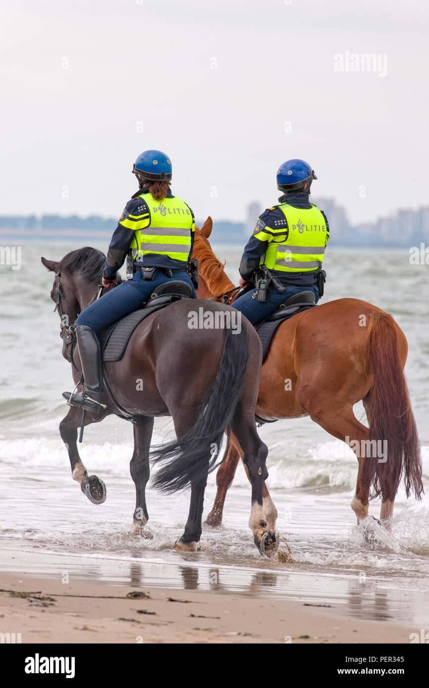 Dutch policemen ride patrol on a horse across the beach of Vlissingen ...