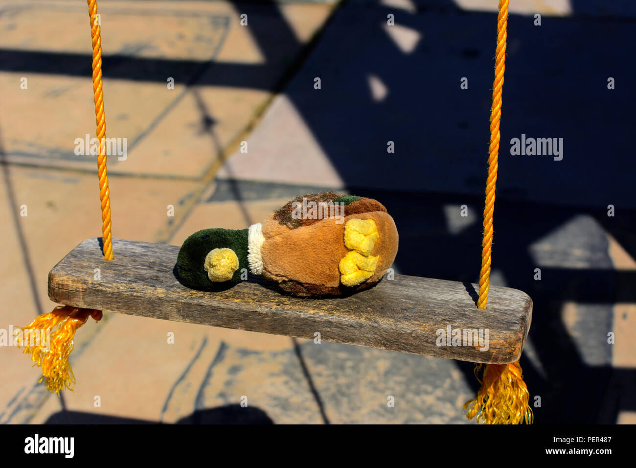Soft children's toy (plush duck) lies on a children's bench for riding ...