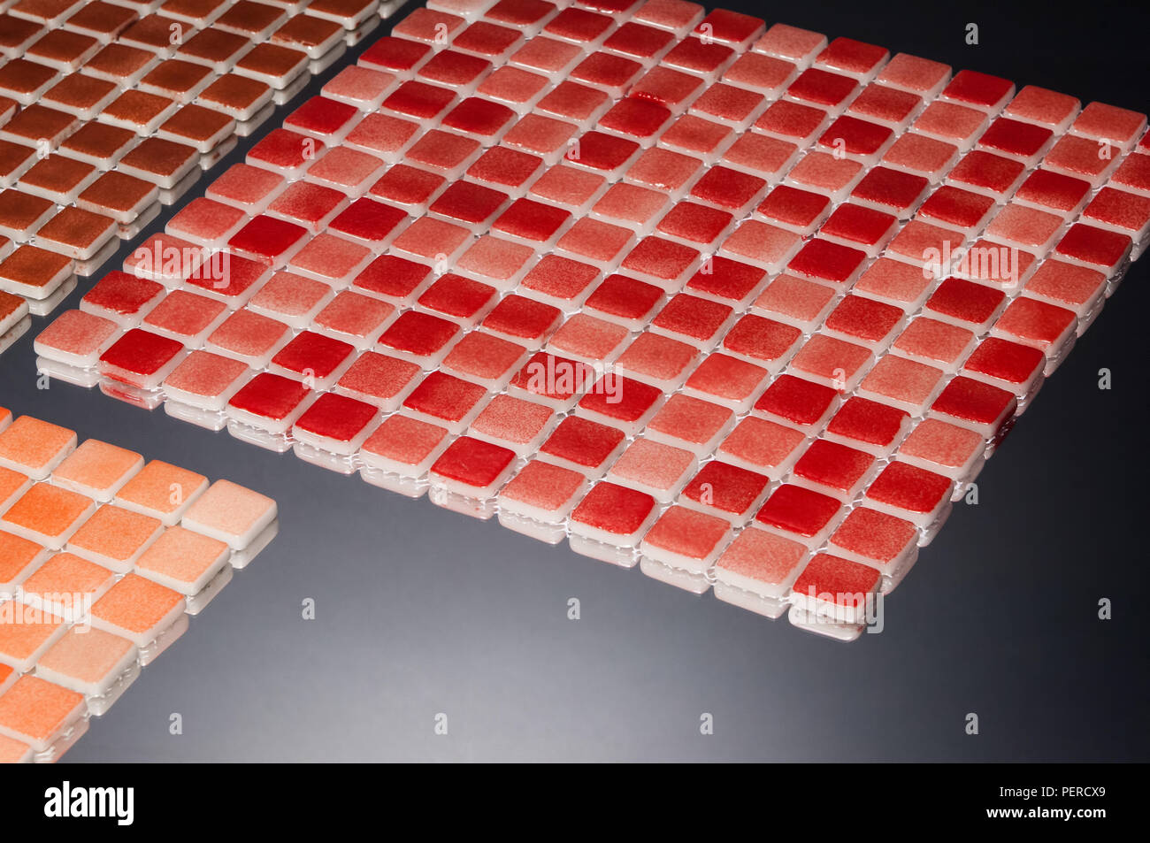 little red and yellow ceramic tile on a grey background with reflection ...