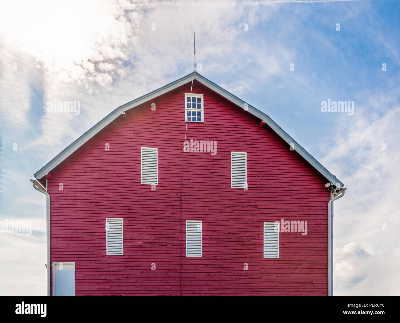 A bright red barn on farmland in western Virginia beneath a bright sun ...