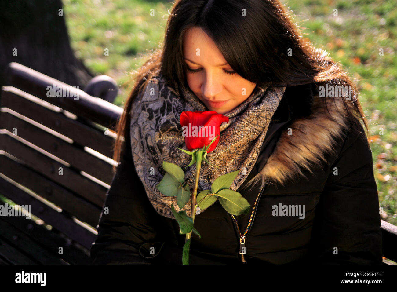 Pretty girl smells red rose and enjoys the scent Stock Photo - Alamy