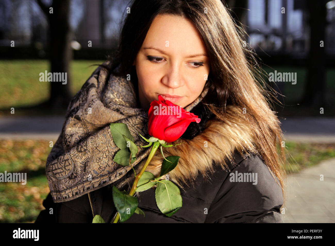Cheerful girl smells red rose and enjoys the scent Stock Photo - Alamy